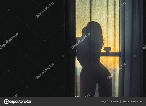 A Naked Female Is Standing By The Window Behind The Curtain And Drinking Coffee At Dawn Stock
