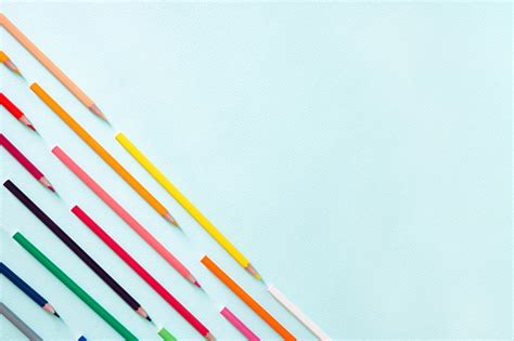 밝은 파란색 배경에 다른 색상의 연필의 수평 미니멀 클로즈업 플랫 레이 구성 왼쪽 아래 모서리에 있는 항목입니다 개체는