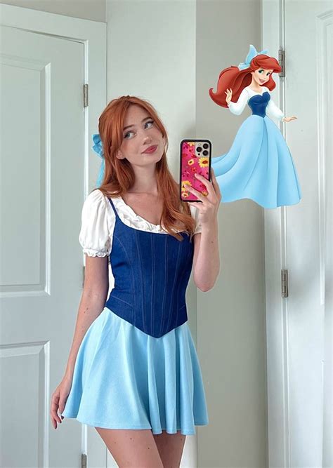 A Woman In A Blue Dress Holding Up A Cell Phone