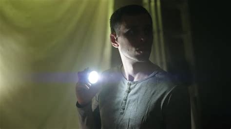 Man With A Flashlight Looking Around In A Dark Room Stock Footage