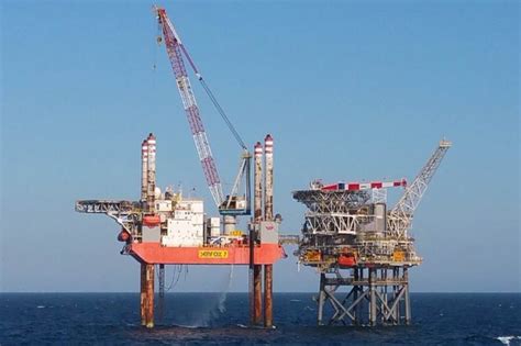 An Oil Rig In The Middle Of The Ocean With Cranes On Its Sides