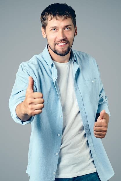 Retrato de un hombre caucásico feliz sonríe y muestra sus pulgares