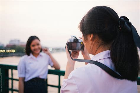 Girls Making Picture Of Each Other By The River At Sunset Time By