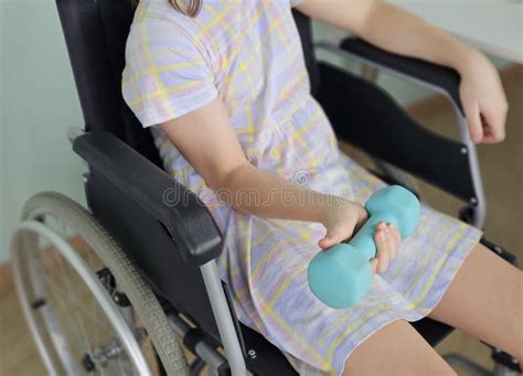 Individual Exercising With Dumbbell While Seated In Wheelchair At