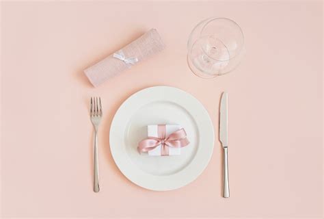 분홍색 배경에 접시와 칼붙이에 선물과 축제 테이블 설정 로맨틱 또는 결혼식 저녁 식사 발렌타인 데이 또는 어머니의 날 배경입니다