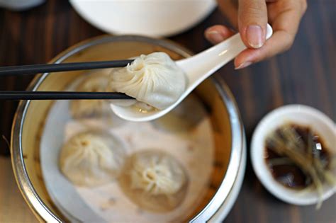 샤오롱바오 수프 만두는 대나무 찜기로 제공되는 전통 중국 음식입니다 젓가락으로 딤섬을 들고 있는 여성의 손을 닫습니다 Baozi