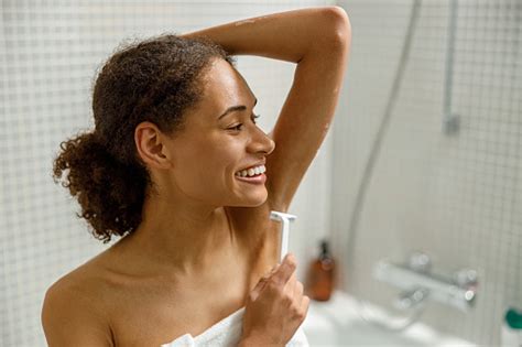 흰 수건을 쓴 여자가 면도기로 겨드랑이를 면도하고 있다 화장실에서의 탈모 절차 겨드랑이에 대한 스톡 사진 및 기타 이미지 겨드랑이 여자 면도 Istock