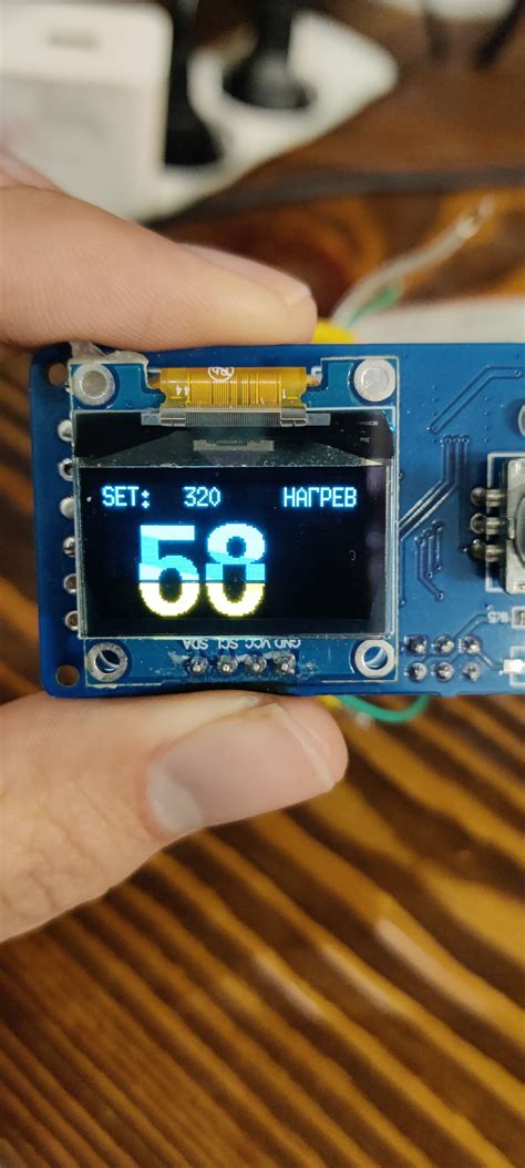 A Person Holding A Small Electronic Device With The Time Displayed On