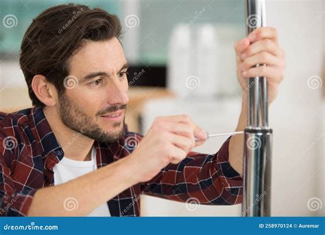 Man Using Screwdriver To Secure Seal Between Two Metal Tubes Stock