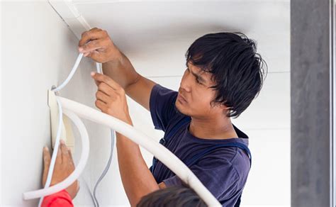 에어컨 기술자 팀은 가정에 새 에어컨을 설치하고 수리공은 에어컨 시스템을 수리하고 기술자는 에어컨 시스템의 전기 케이블 와이어로 작업합니다 30 34세에 대한 스톡 사진 및