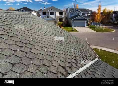 Detail Of Well Worn Rounded Roof Shingles With Neighbourhood Houses