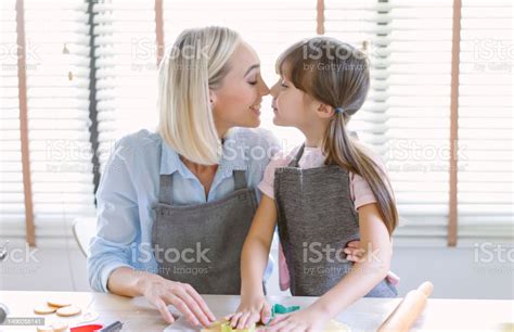 아름다운 어머니와 그녀의 작은 귀여운 딸이 함께 요리하고 얼굴을 마주 보며 코를 만지고 집에서 여가 시간을 보내고 쿠키를 굽는 초상화 가족 활동을 함께 즐기십시오 30 34