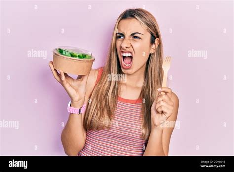 Beautiful Hispanic Woman Eating Salad Angry And Mad Screaming Frustrated And Furious Shouting
