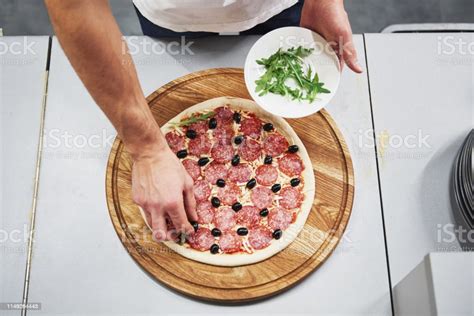 진행 중인 작업 레스토랑에서 주문에 대 한 맛 있는 피자를 만들기 위해 올리브를 퍼 팅 화이트 셔츠 베이커의 평면도 만들기에