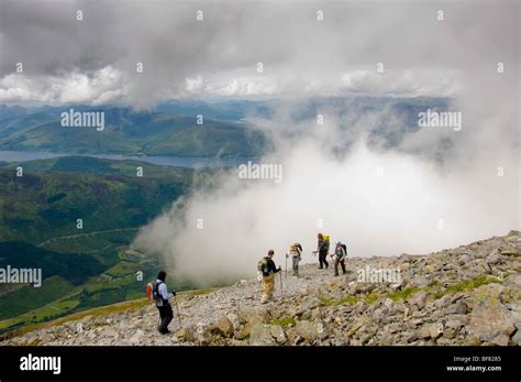 Walkers Using Trekking Poles On The Rocky Path Above The Clouds On Ben