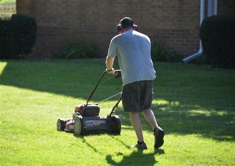 Premium Photo Rear View Of Man Mowing The Grass