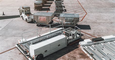 다양한 유형의 여러 트랙터가있는 이륙 현장의 기계보기 하나는 식사와 수하물로 컨테이너를 운반하고 두 번째는 비어 있습니다 빈 수하물 카트 엘 파트 바르셀로나 공항