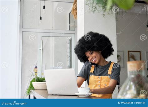 Happy Young African American Woman Talking On Phone Using Laptop In