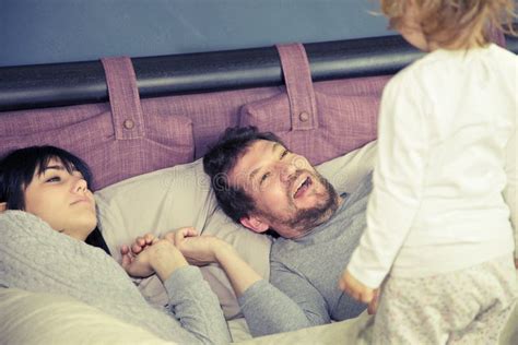 Niña Que Despierta La Madre Y Al Padre En Cama Foto De Archivo Imagen