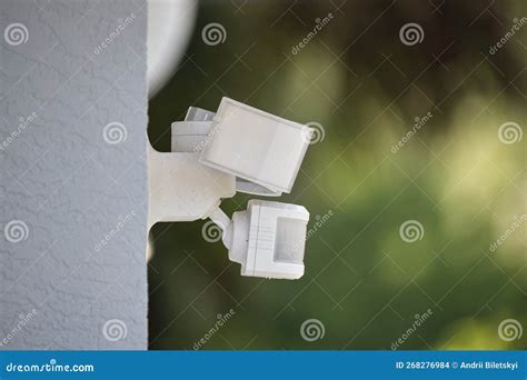 Motion Sensor With Light Detector Mounted On Exterior Wall Of Private