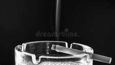 Burning Cigarette In Glass Ashtray Smoke Rising From Cigarette In Ash