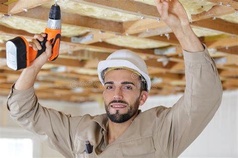 Builder Using Cordless Drill On Wooden Ceiling Overhead Stock Image