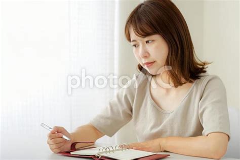 手帳を見ながら予定を考える若い女性 No 27108459｜写真素材なら「写真ac」無料（フリー）ダウンロードok