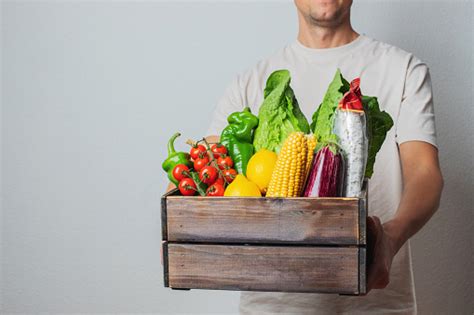 배달 개념 젊은 백인 배달 남자 식료품 야채와 과일의 나무 상자를 들고 상점에서 회색 스튜디오 배경에 격리 복사 공간 30 34