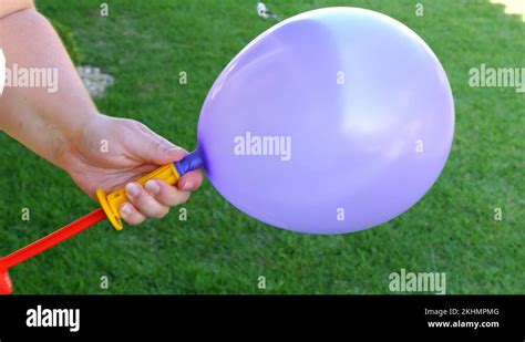 Woman Inflating A Violet Balloon With A Hand Pump Close Up Shot Stock