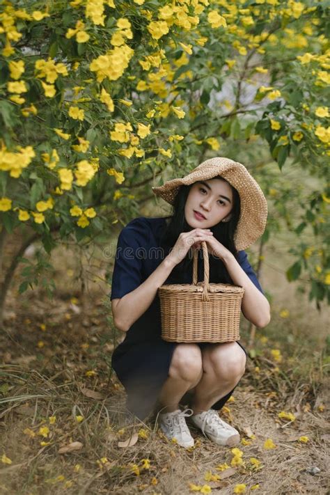 Sitting Thai Girl With Her Basket And Yellow Flowers Stock Image