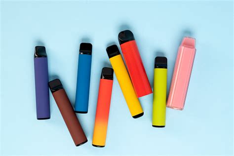 파란색 배경에 그림자가있는 다채로운 일회용 전자 담배의 레이아웃 현대 흡연 Vaping 및 니코틴의 개념 위쪽 보기 전자담배에