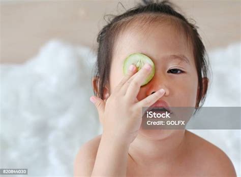 귀여운 작은 아이 소녀 그녀의 눈에 오이 피부 관리에 대 한 개념의 한 조각 개념에 대한 스톡 사진 및 기타 이미지 개념
