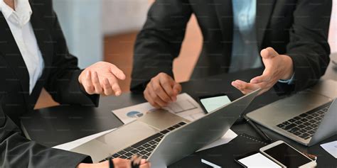 현대 사무실을 배경으로 검은 회의 테이블에 함께 앉아 컴퓨터 노트북과 그래픽 차트로 사업 계획에 대해 논의하는 비즈니스 임원의 잘린 이미지 사진 Unsplash의 태국 이미지