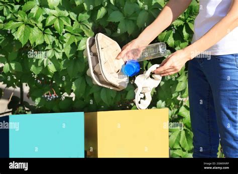 Woman Throwing Cardboard And Plastic Garbage In Container Outdoors