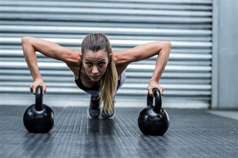 Premium Photo Muscular Woman Doing Pushups With Kettlebells