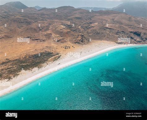 Aerial View Of Turquoise Waters Meeting A Pristine White Beach Against