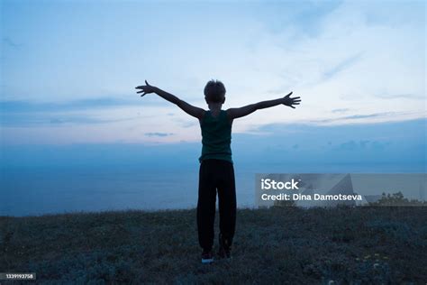 한 어린이가 꽃이 만개한 허브가 있는 초원에 서 있습니다 바다는 멀리서 볼 수 있습니다 소년은 새의 날개처럼 팔을 벌려 했다 자연에서 짧은 머리를 가진 소녀 아름다운 여름