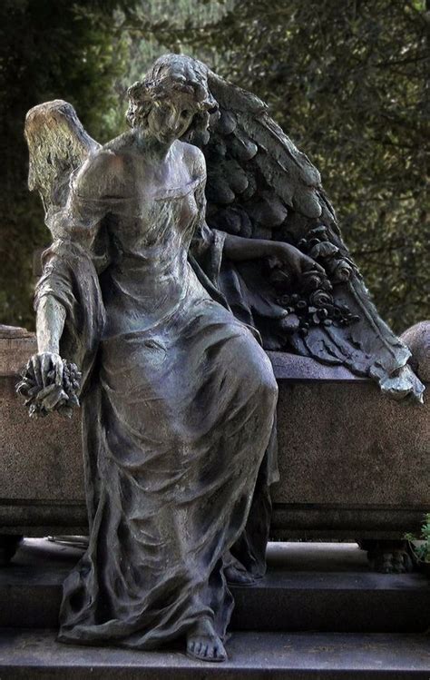An Angel Statue Sitting On Top Of A Stone Bench