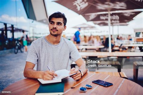 잘생긴 남성 디자이너 아이디어 노트와 야외 카페 휴식에 유제품 만들기 일정에 대상의 체크 리스트를 만드는 Pensieve Hipster 남자의 테라스에 앉아 계획을 만드는
