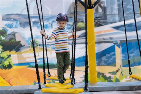 실내 장애물 코스 높은 로프 공원을 통과하는 모험 공원에서 등반하는 백인 소년 프리미엄 사진