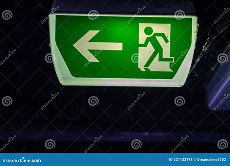 Green Exit Sign With Running Person And Green Arrow Shows Guidance System Signage In A Parking