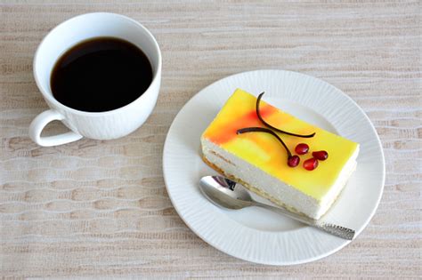 찻 숱가락과 커피 한 잔과 함께 흰색 접시에 분리 된 건강한 레몬 치즈 케이크 조각 거품 내기에 대한 스톡 사진 및 기타 이미지