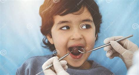 Niño árabe Lindo Sentado En Una Silla Dental Con Boca Abierta Durante