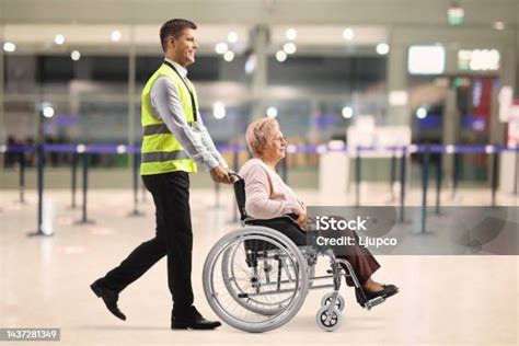 공항 터미널에서 휠체어를 탄 노인 여성을 밀고 있는 공항 직원의 전체 길이 프로필 사진 공항에 대한 스톡 사진 및 기타 이미지