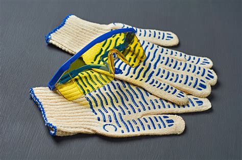 건물 용접기 터너 및 기타 직물 장갑 근처의 노란색 유리와 파란색 프레임에 대한 근로자를위한 현대 보호 안경은 어두운 콘크리트 책상에 놓여 있습니다 클로즈업 개성 개념에