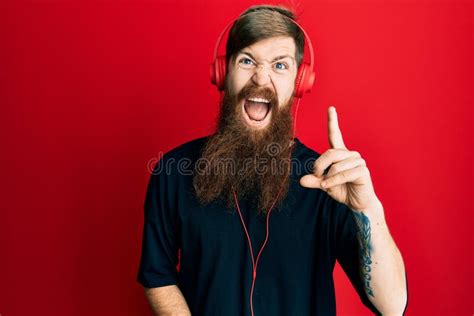 Redhead Man With Long Beard Listening To Music Using Headphones