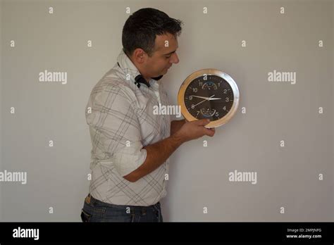 image of a man holding a wall clock while setting the correct time