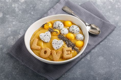 회색 배경에 음료수 그릇입니다 맛 있는 망고 스무디는 Chia 씨앗 망고 및 드래곤 과일 얹은 사랑 쿠키 편지 위에 만들어진 단어 건강 한 아침 식사입니다 공간에 복사