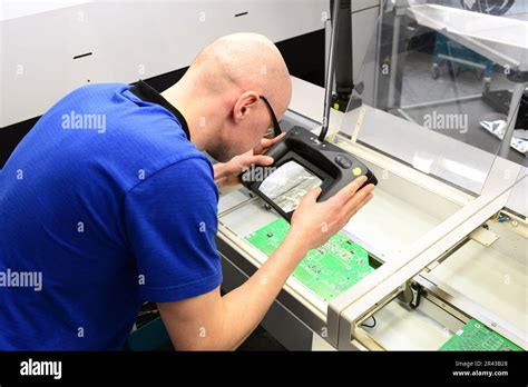Quality Control In The Production Man Checks Board For Defects Manufacturing In A High Tech