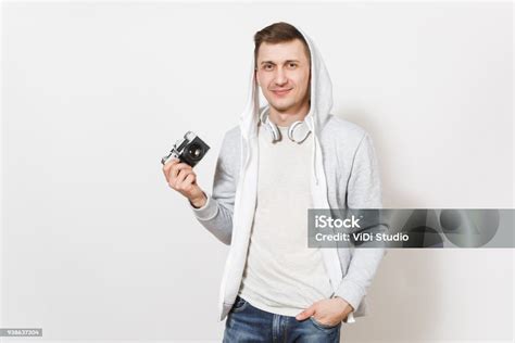 젊은 잘생긴 웃는 남자 학생 T셔츠와 헤드폰 후드와 함께 빛 셔츠에 복고풍 카메라를 보여줍니다 그리고 흰색 배경에 고립 된